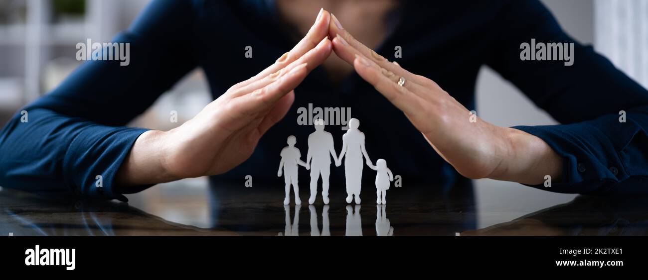 Businessperson's Hand Protecting Family Figures Stock Photo - Alamy