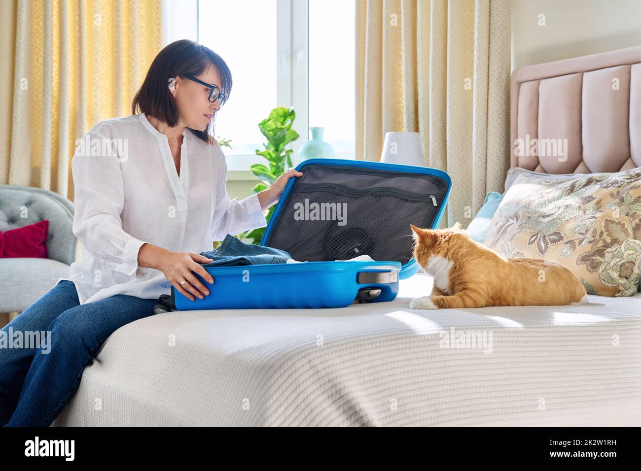 Happy woman packing suitcase with pet cat Stock Photo - Alamy