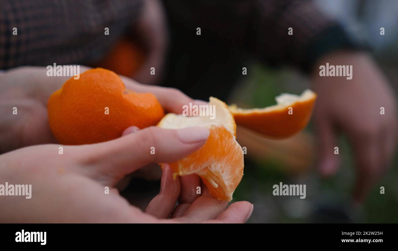 Woman hand peeling ripe sweet tangerine, close up above the fireplace ...