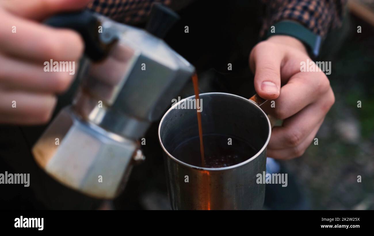Young pair in forest. Woman pours tea, coffee from a Aluminium Coffee ...