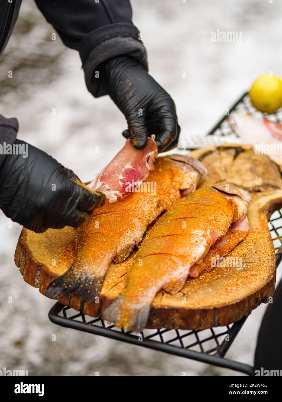 Grillman prepares trout for grilling, wraps bacon around fish Stock ...