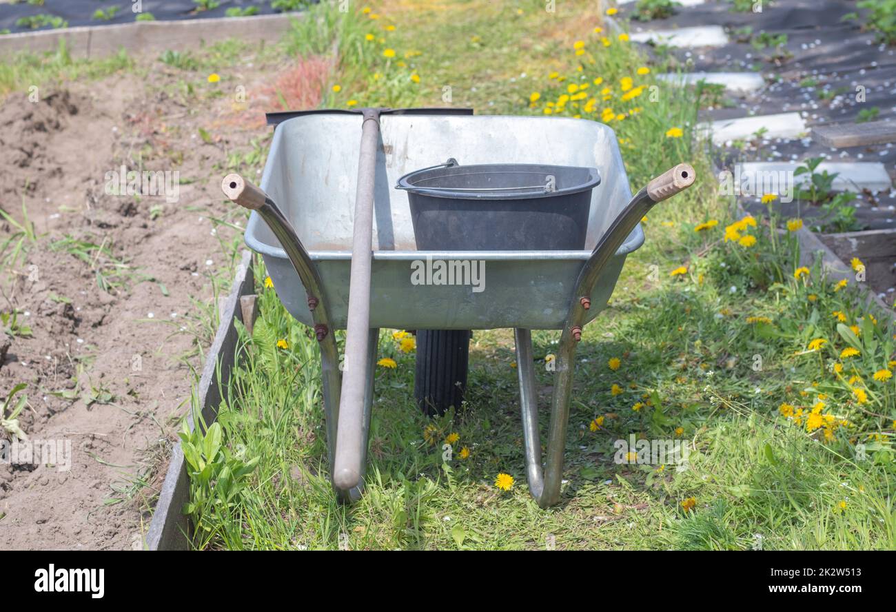 Gray metal garden wheelbarrow with two handles and one wheel. The ...