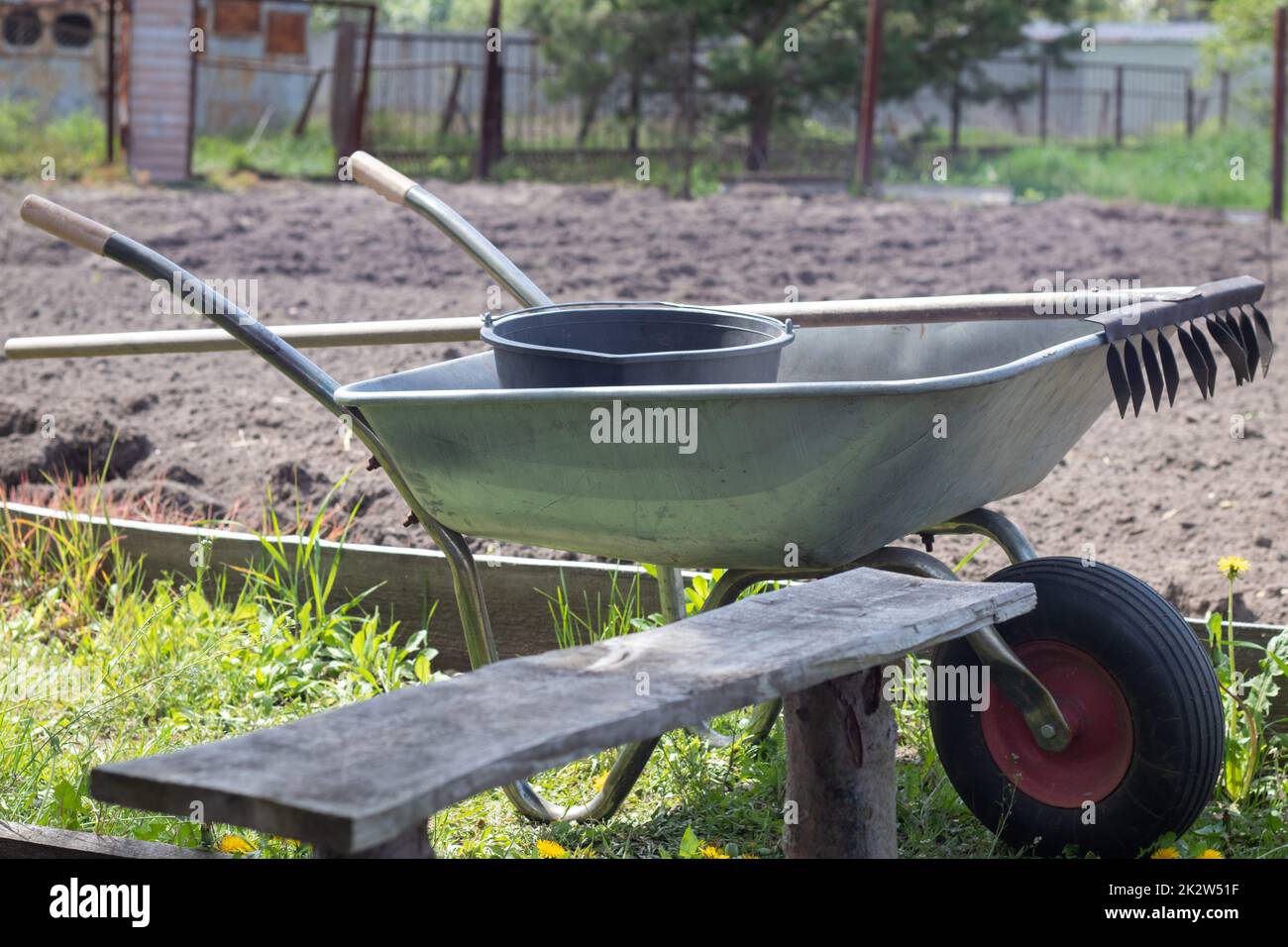 Gray metal garden wheelbarrow with two handles and one wheel. The ...