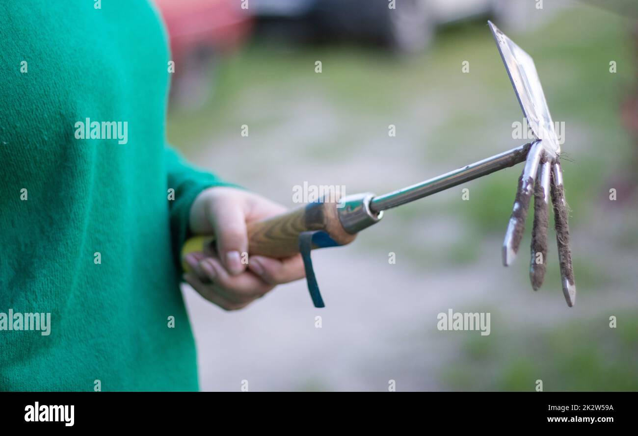 Caucasian woman gardener in the garden shows a rake. The concept of ...