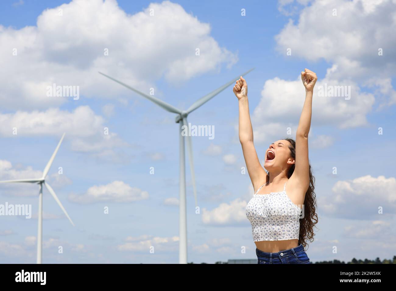 Excited woman raising arms celebrating in a wind farm Stock Photo - Alamy