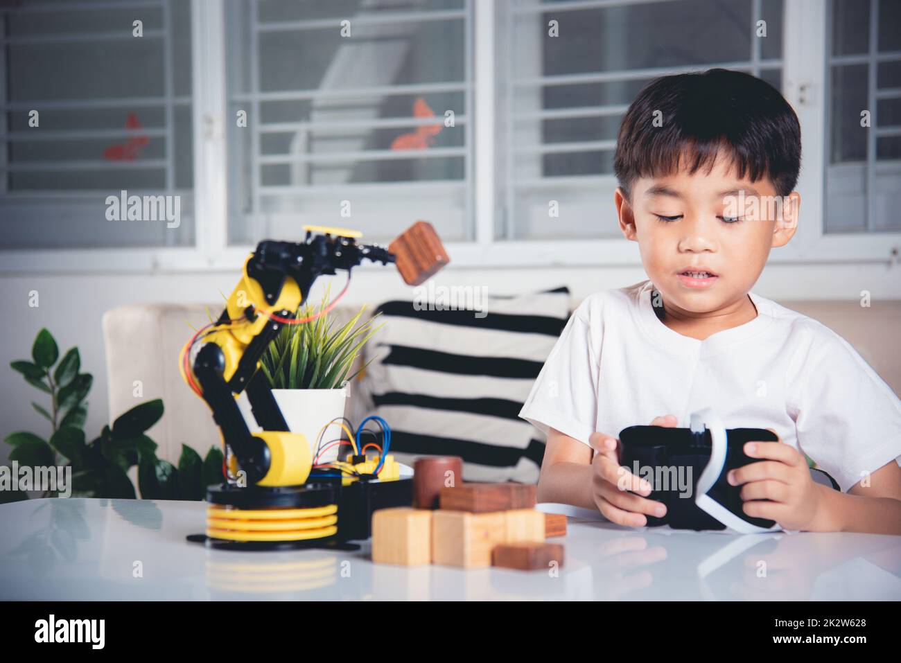 Happy Asian little kid boy using remote control playing robotic machine ...