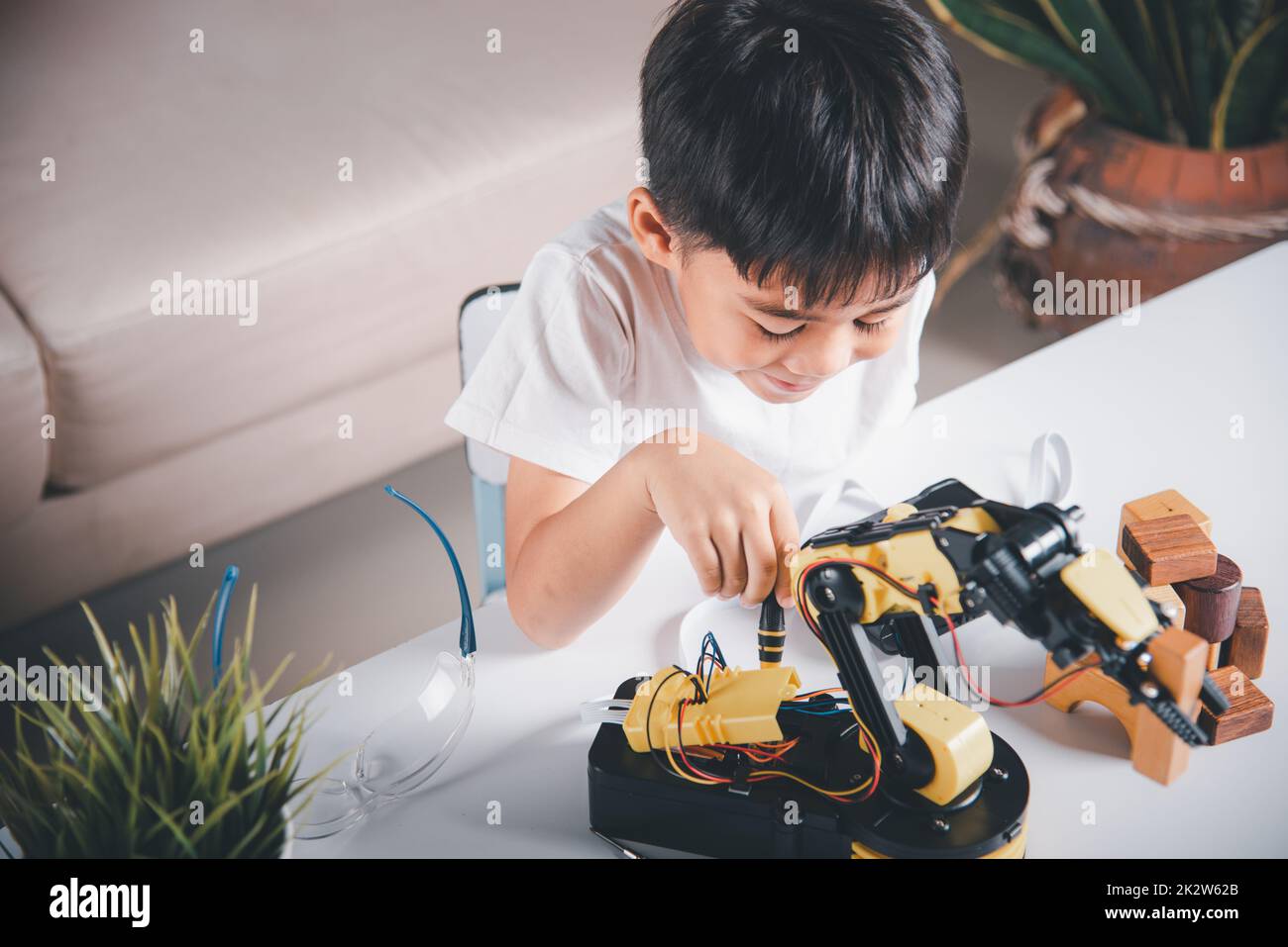 Happy Asian little kid boy using screwdriver to fixes screws robotic ...