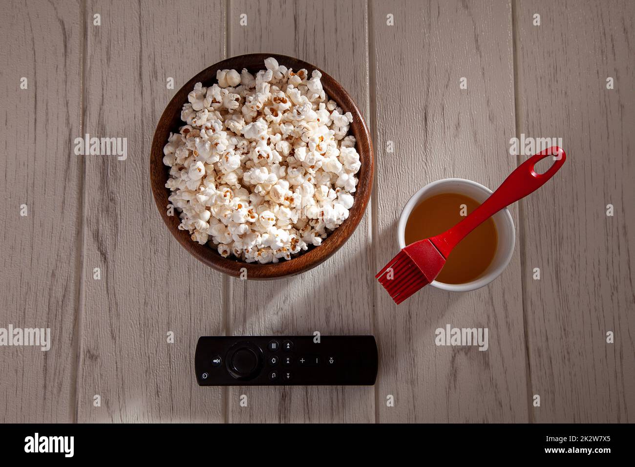 A top view of a bowl of popcorn, a remote controller, and a bowl of ...