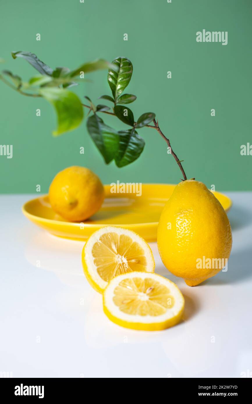 A vertical shot of aesthetic lemons with leaves on green background ...