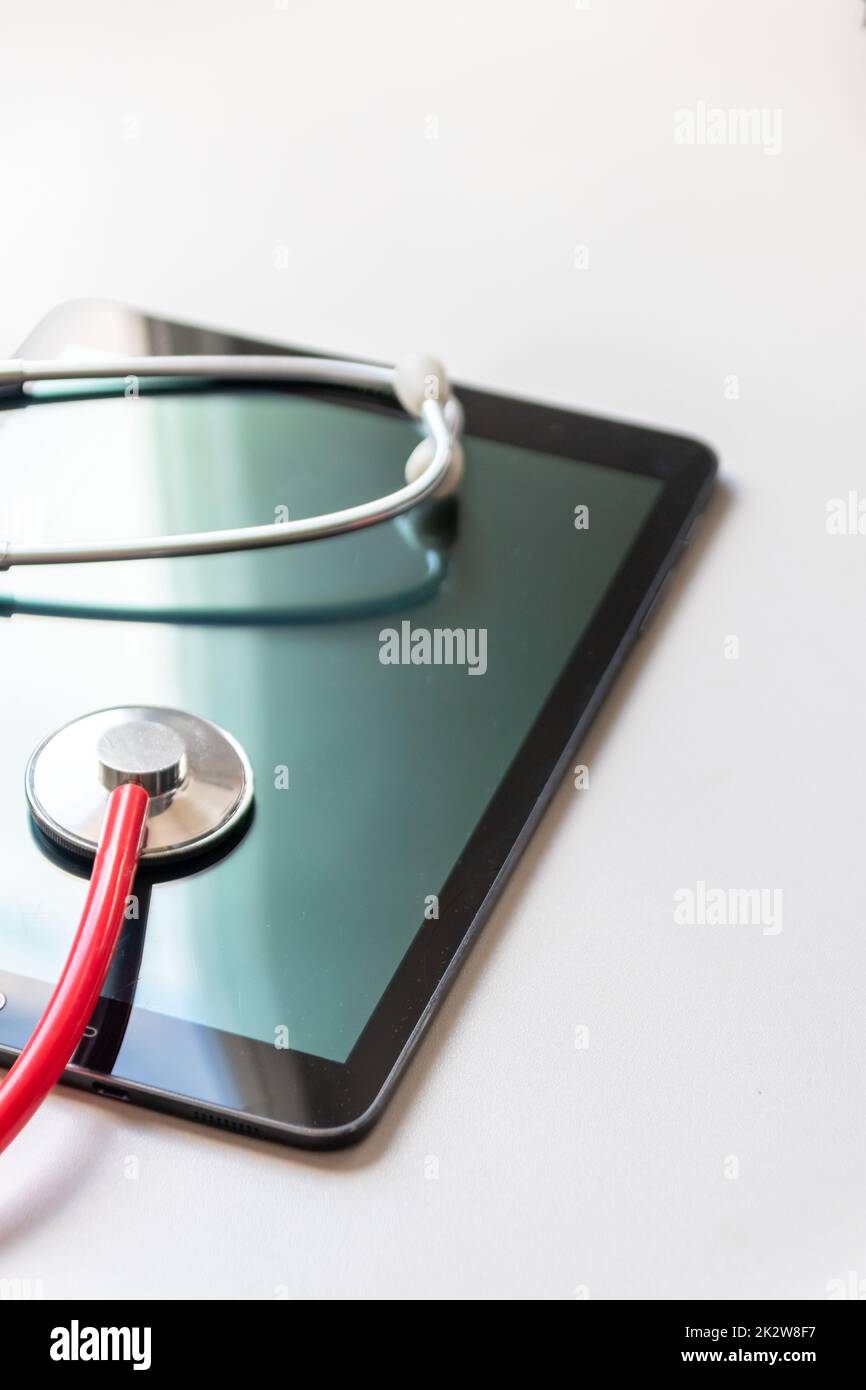 Red stethoscope on black tablet device shows health records and digital ...