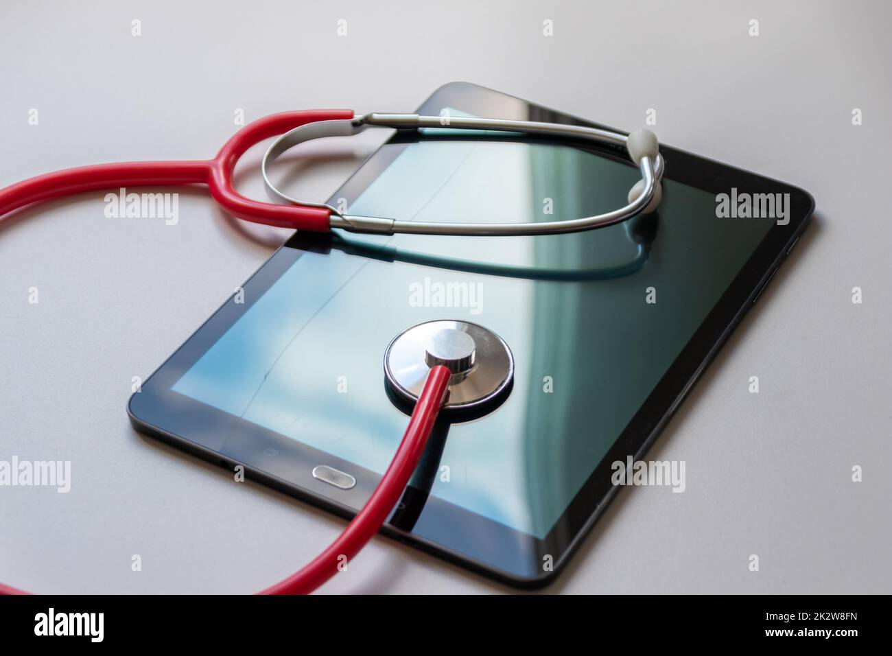 Red stethoscope on black tablet device shows health records and digital ...
