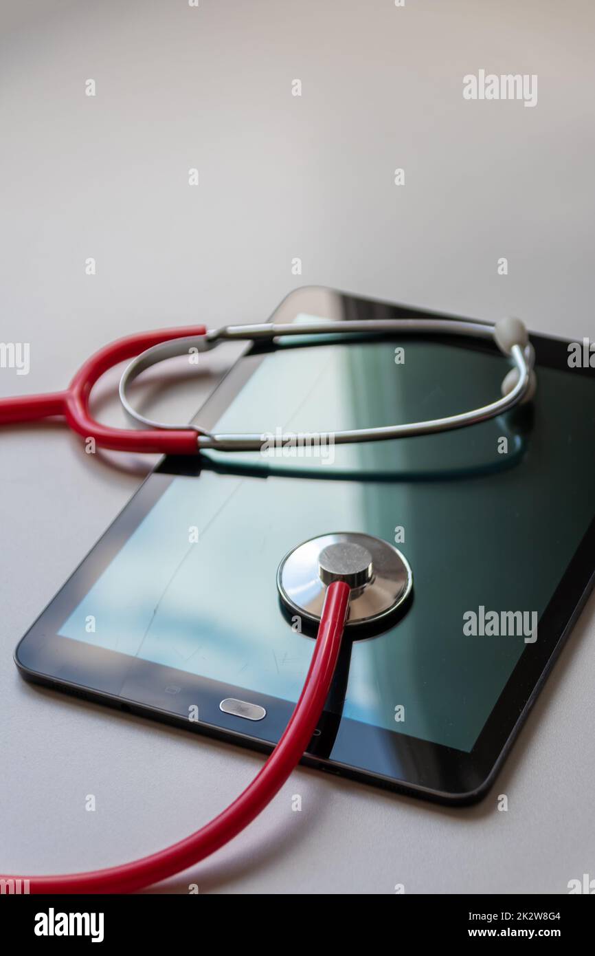 Red stethoscope on black tablet device shows health records and digital ...