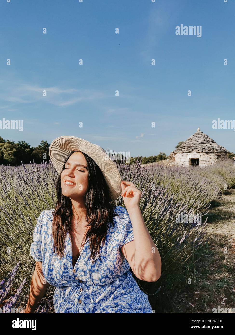 A vertical shot of a beautiful young Caucasian woman in a straw hat in ...