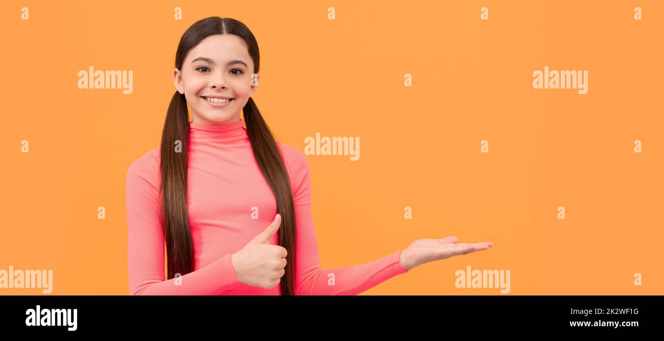 happy teen girl presenting copy space on orange background show thumb ...