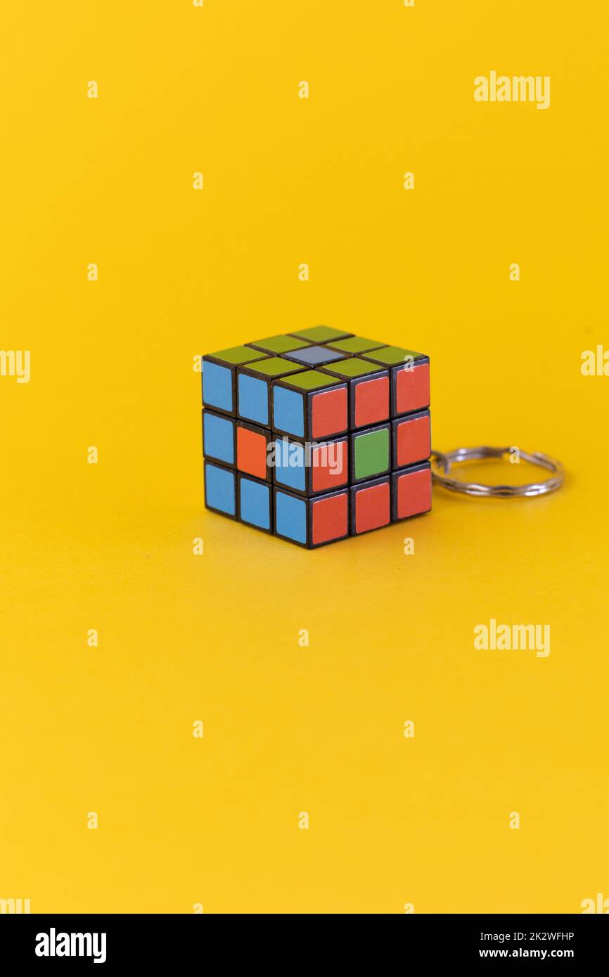 The vertical view of a Rubik's cube key chain on the yellow background ...