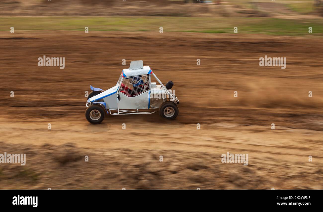 A small sports buggy racing vehicle with a child driving on a rally competition track during ...
