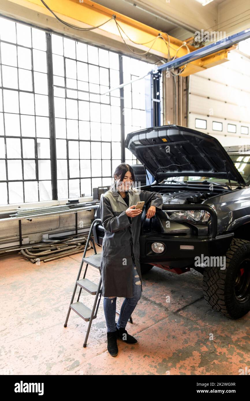 Female auto mechanic using smart phone at modified SUV in garage Stock ...