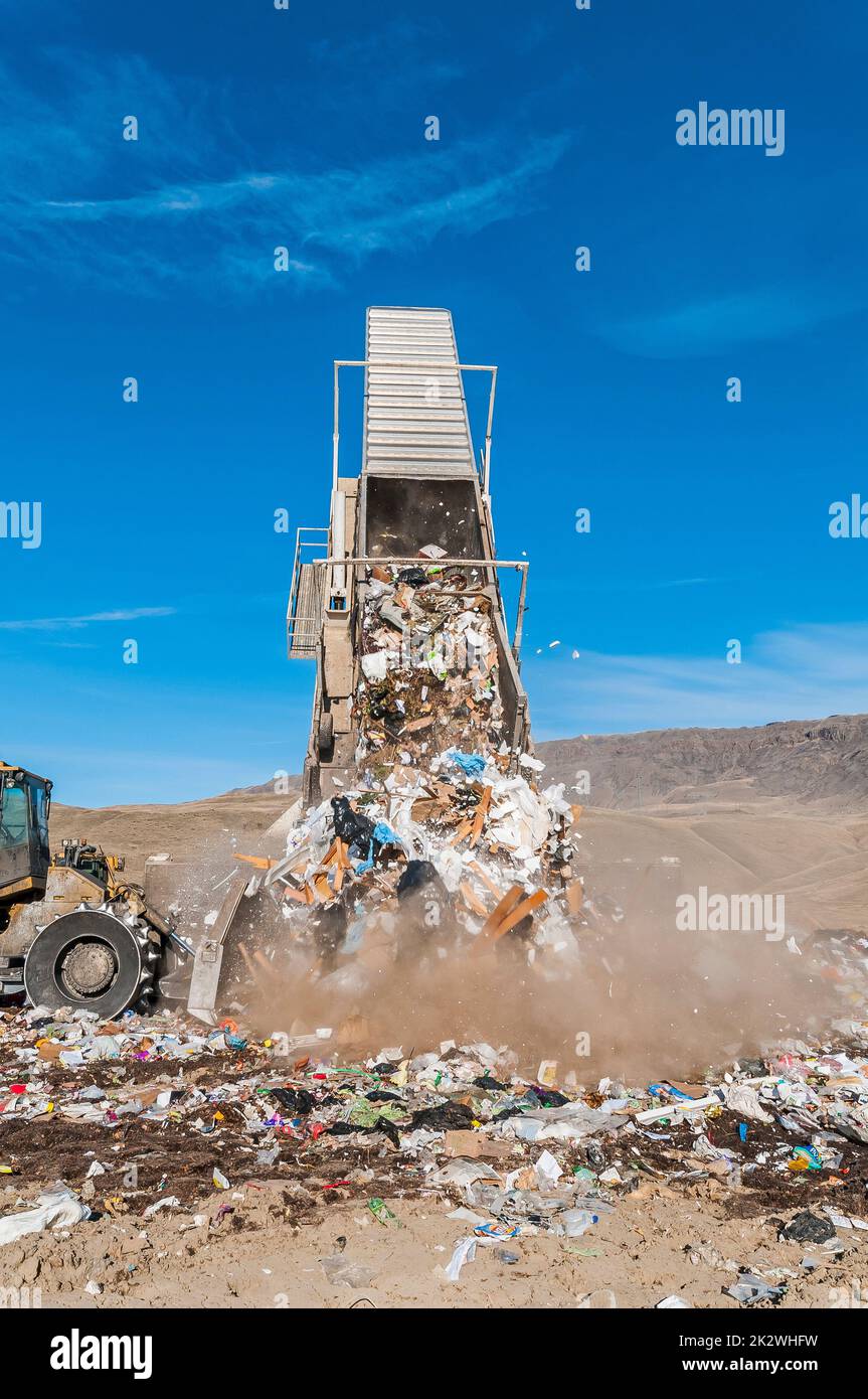 A trailer from a semitrailer truck is in a landfill tipper being raised ...