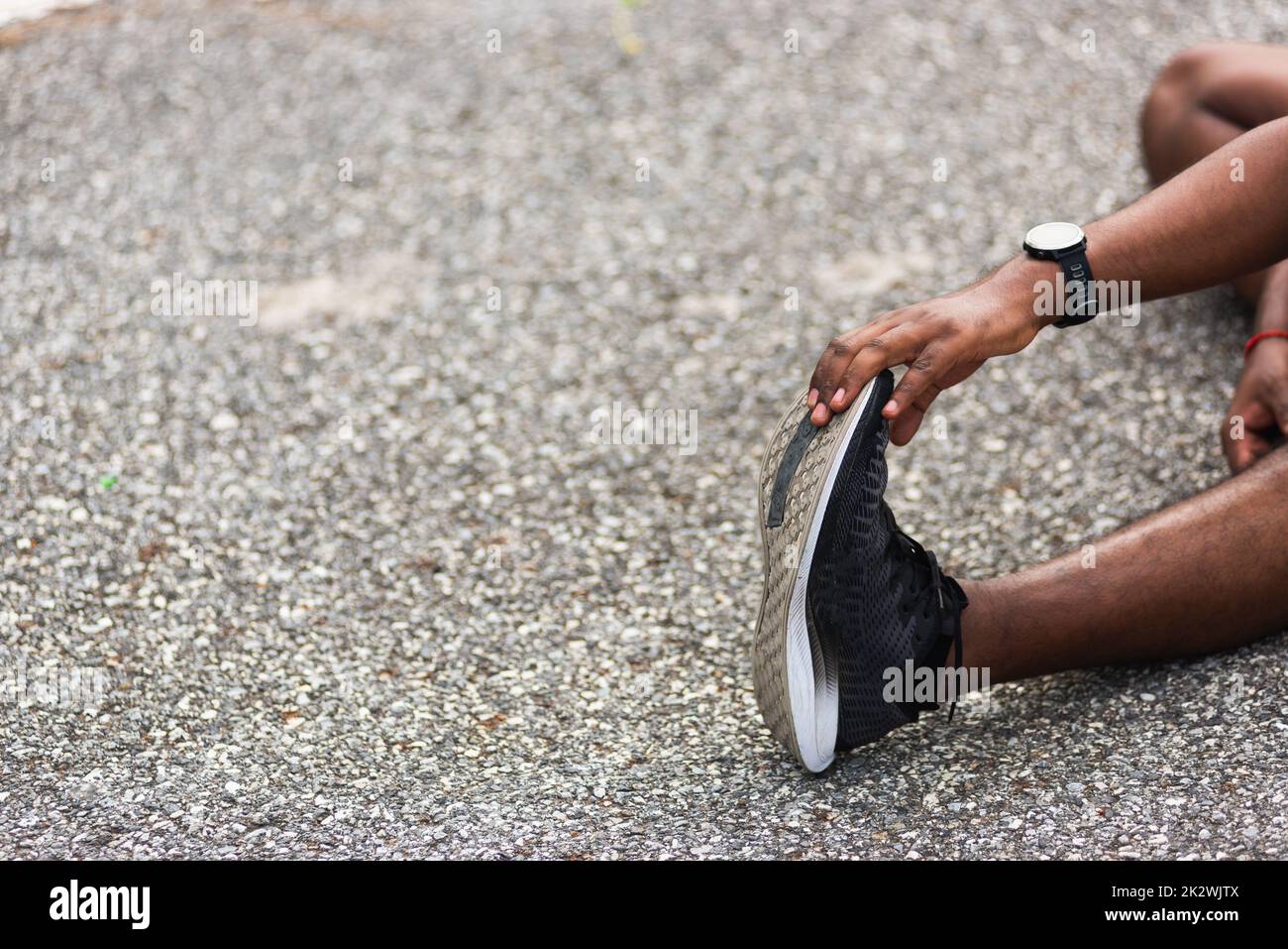 sport runner black man wear watch he sitting pull toe feet stretching ...