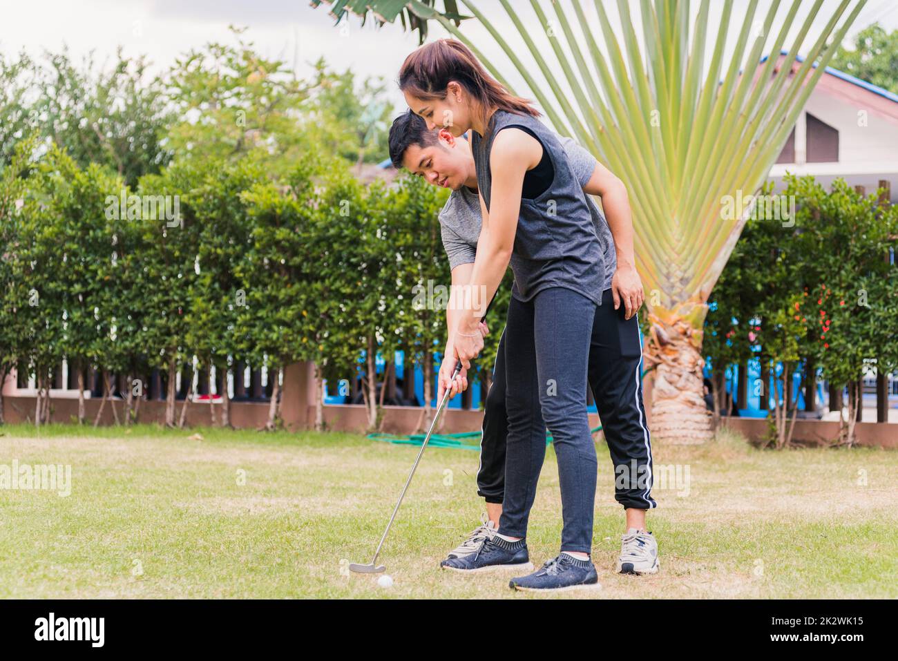 young man support teaching training woman to play perfect golf while ...