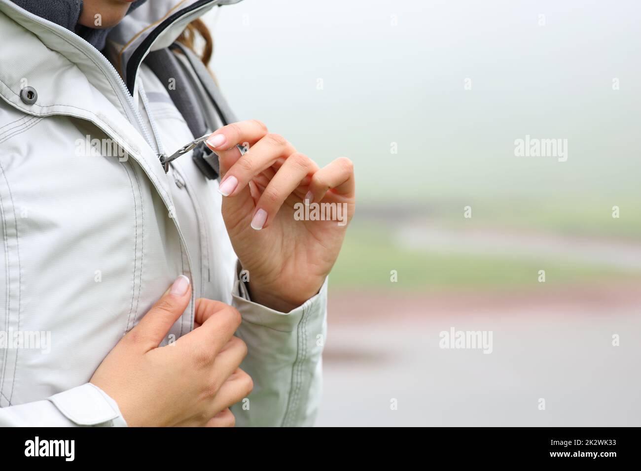 Trekker zipping up jacket in the mountain a foggy day Stock Photo - Alamy