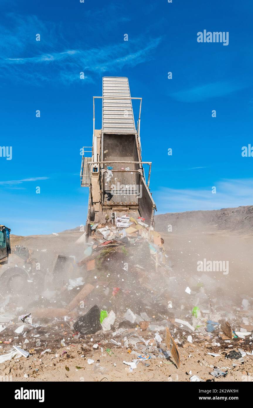 A trailer from a semitrailer truck is in a landfill tipper being raised ...