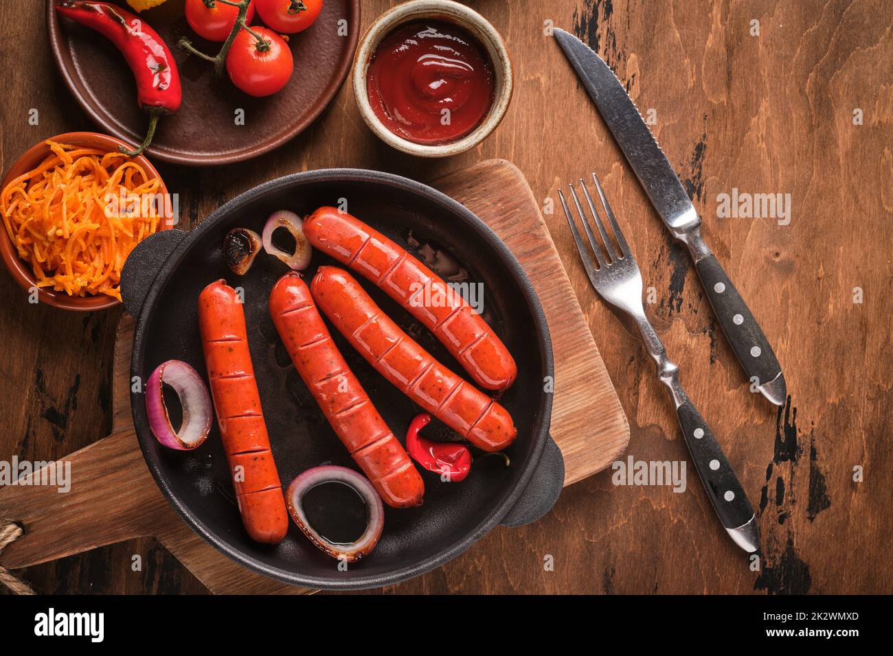 Grilled sausages in a pan with onions and vegetables Stock Photo - Alamy