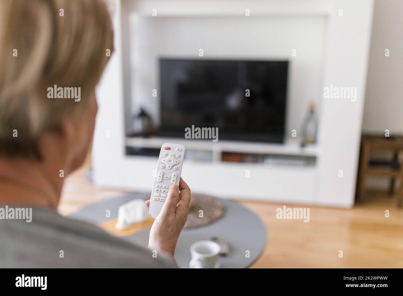 Senior woman with remote control watching tv Stock Photo - Alamy