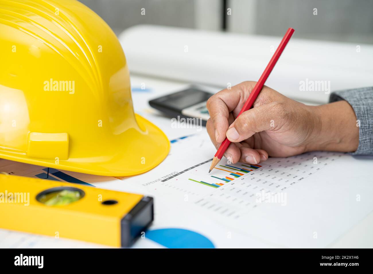Asian engineer with plan project blueprint, graph and yellow helmet and ...
