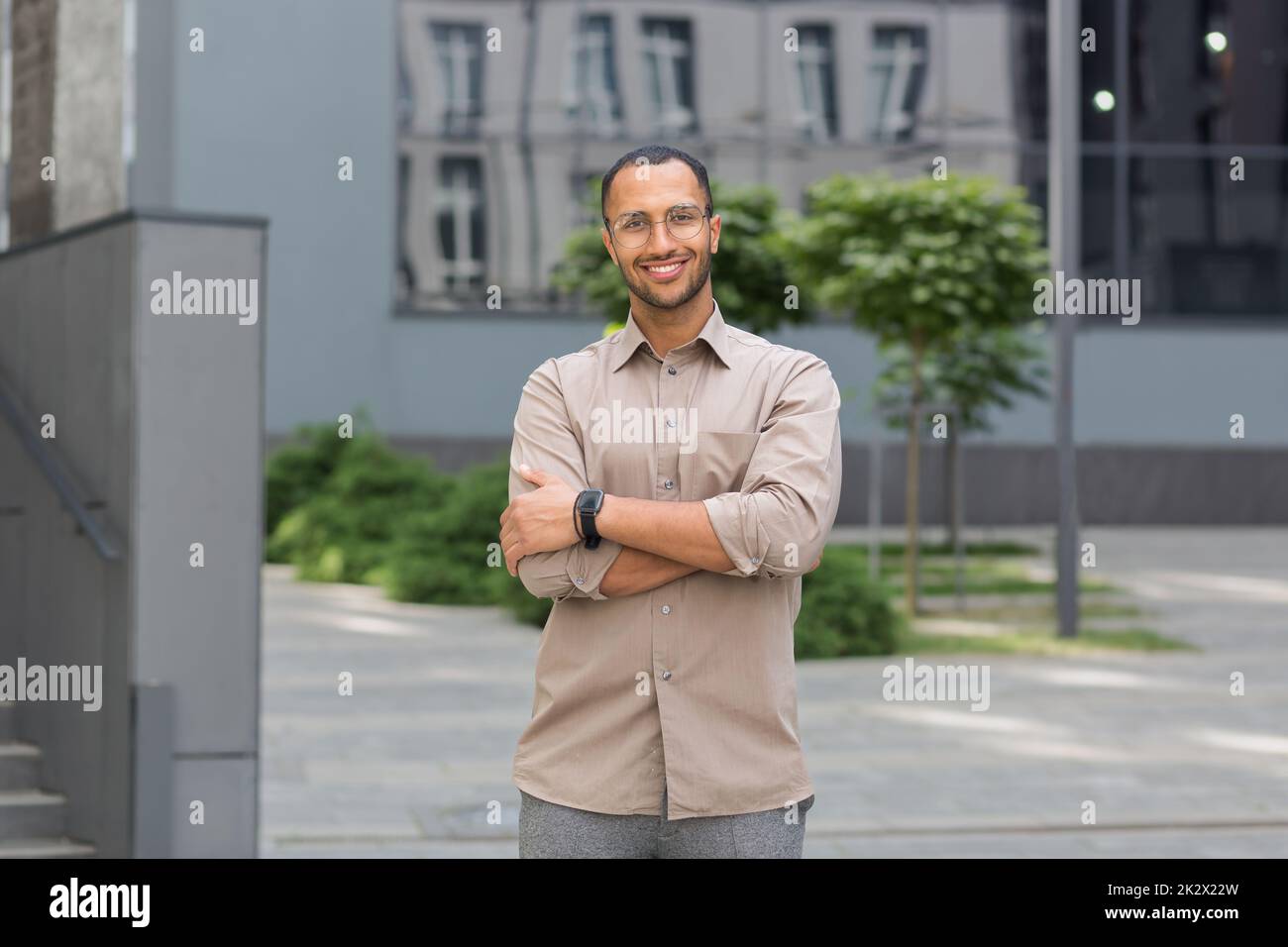 Young successful businessman smiling and looking at camera with crossed ...