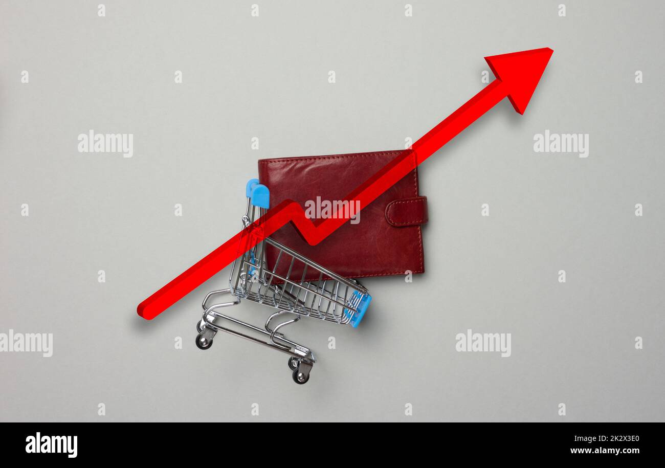 A brown leather wallet lies in a miniature cart and a red arrow is up ...
