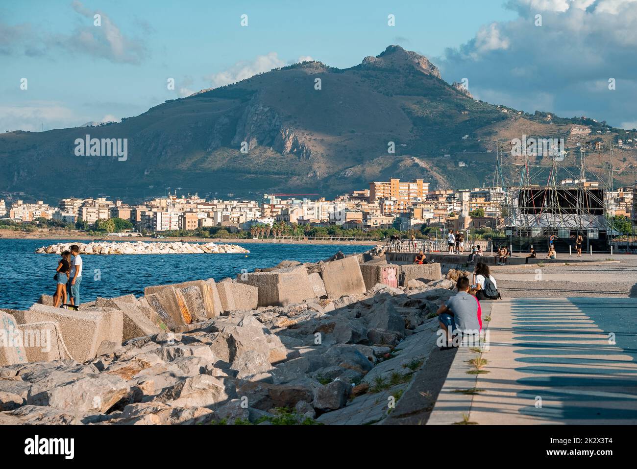 Tourists exploring on promenade with mountain and harbor city in ...