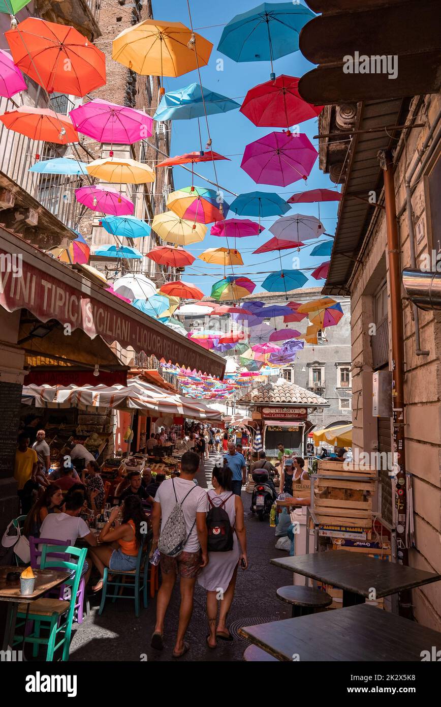 Tourists enjoying at cafe under multi colored umbrellas hanging amidst ...