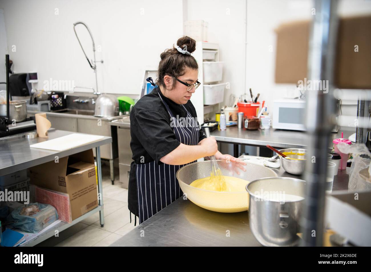 Female baker mixing ingredients in commercial bakery kitchen Stock ...
