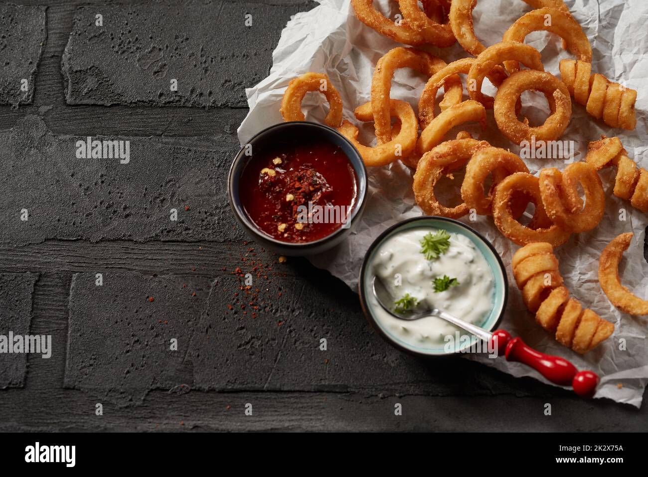 Fried potatoes and onion rings on paper Stock Photo - Alamy