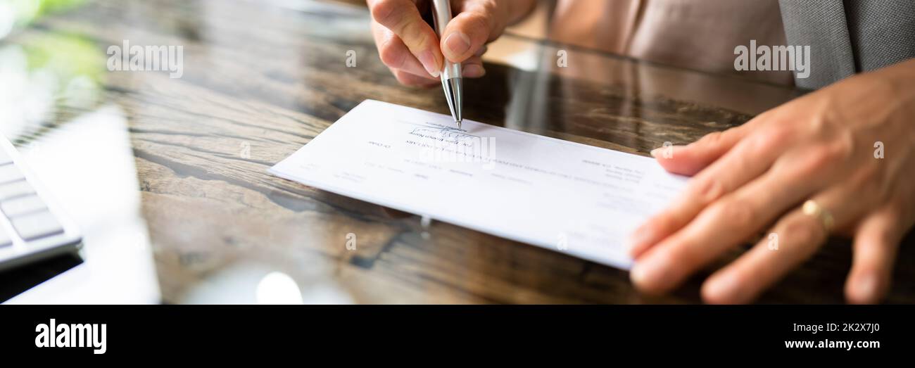 Businessperson's Hand Signing Cheque Stock Photo - Alamy