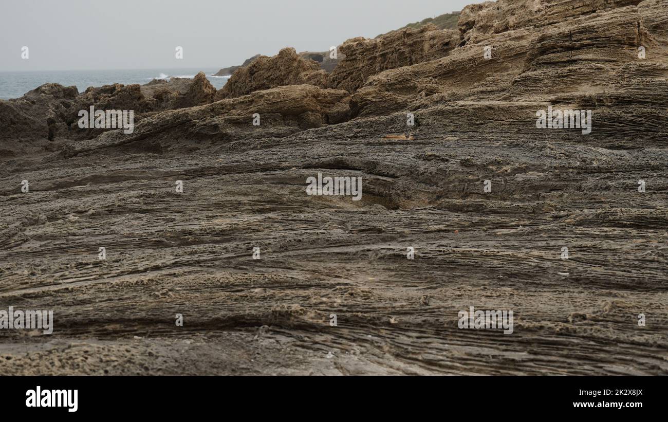 Volcanogenic rock slabs on the seashore. Natural rocky breakwater at ...