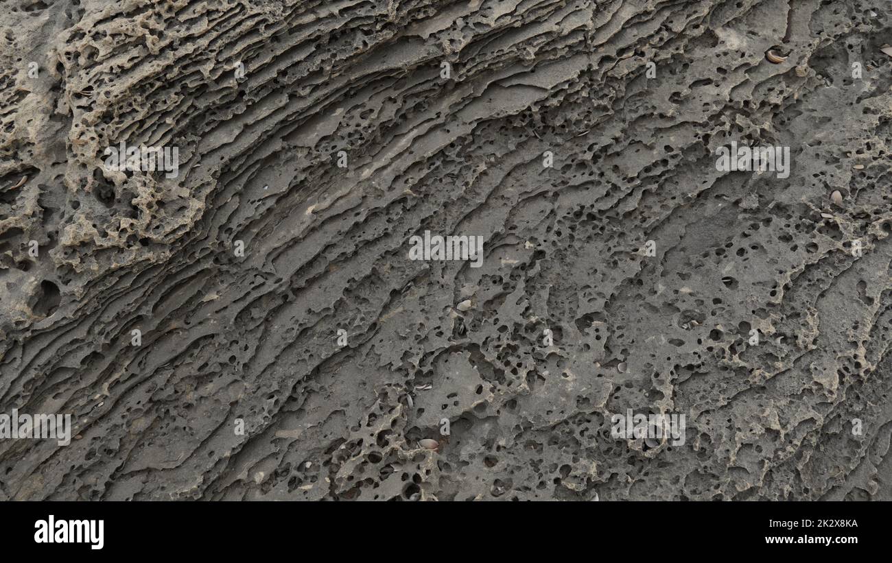 Volcanogenic rock slabs on the seashore. Natural rocky breakwater at ...