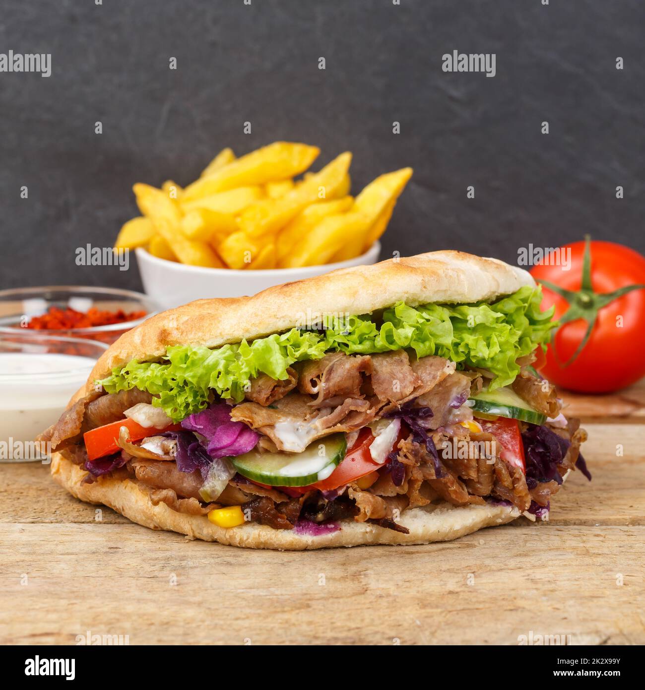 DÃ¶ner Kebab Doner Kebap fast food in flatbread with fries on a wooden ...