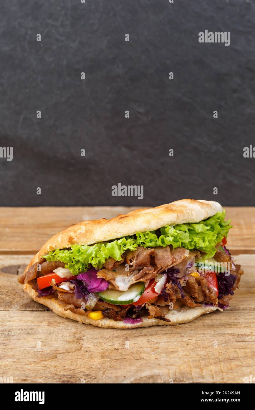 DÃ¶ner Kebab Doner Kebap fast food in flatbread on a wooden board ...