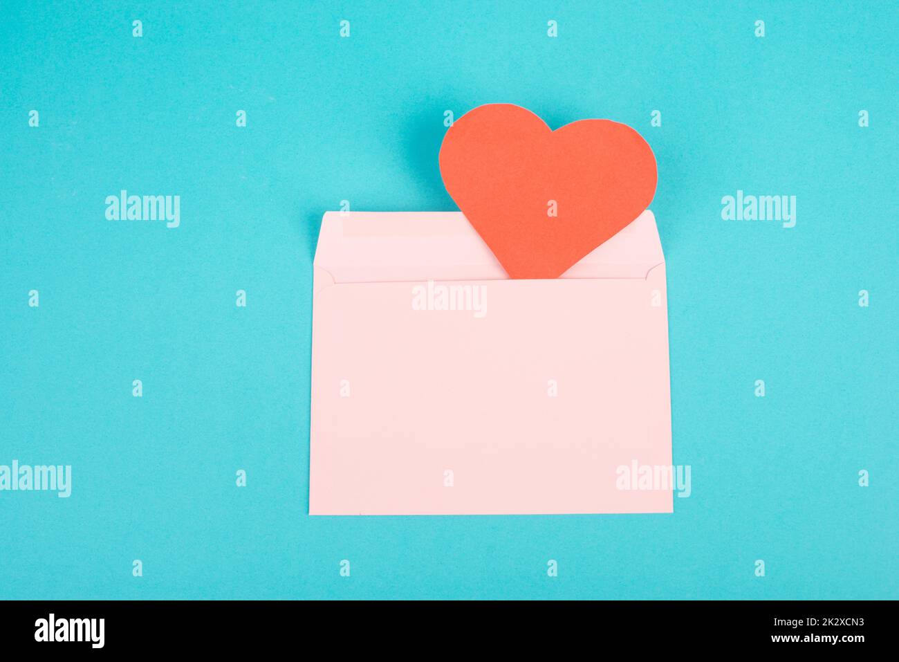 Pink envelope with a red heart, empty copy space, blue background ...