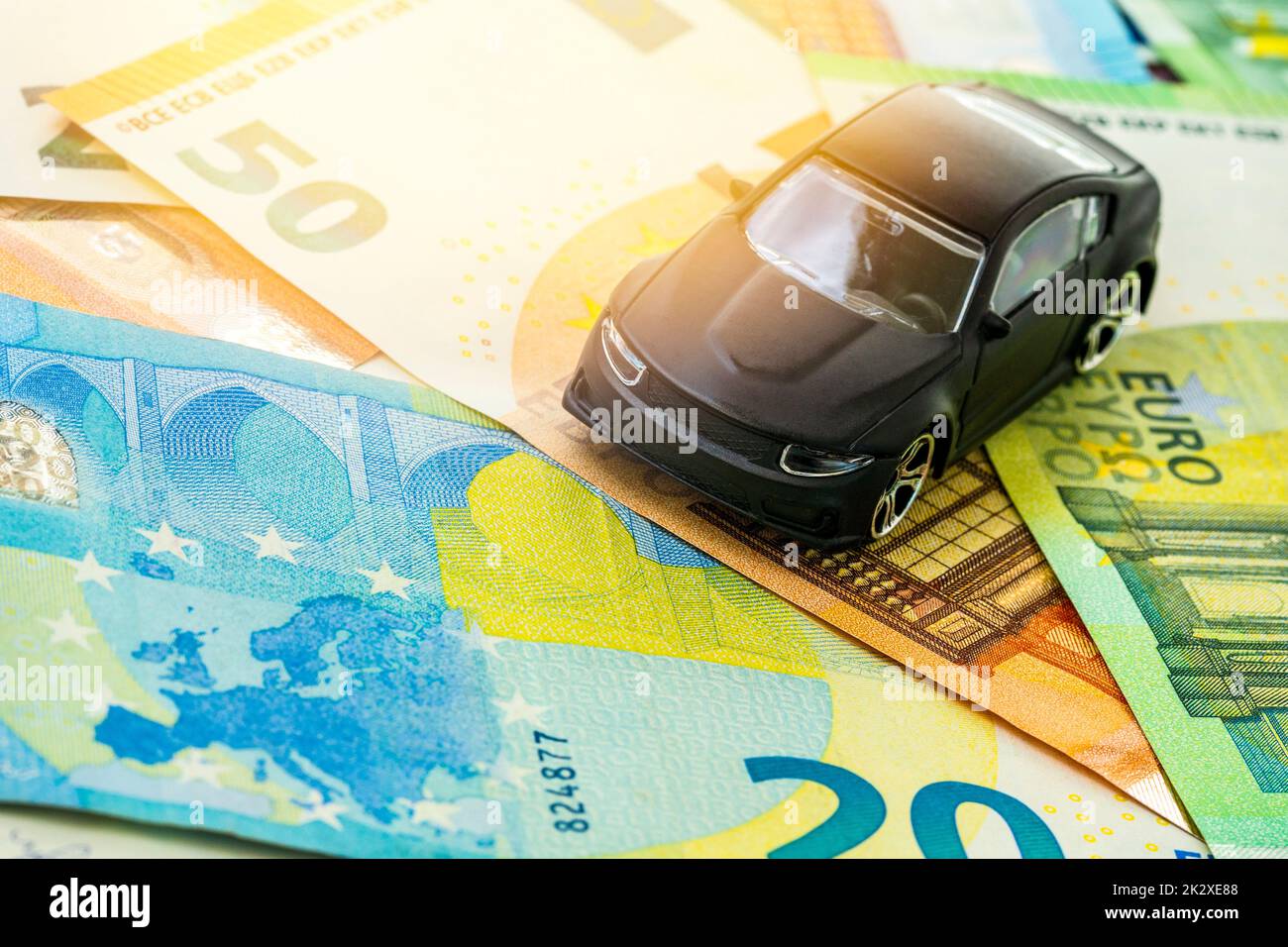 Black toy car on different euro banknotes Stock Photo - Alamy