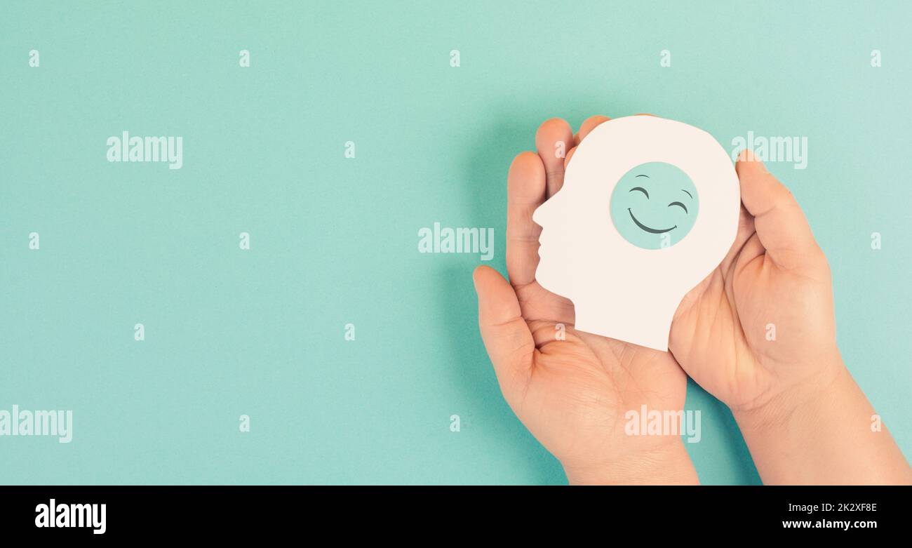 Holding a head with a smiling face in the hands, mental health concept ...