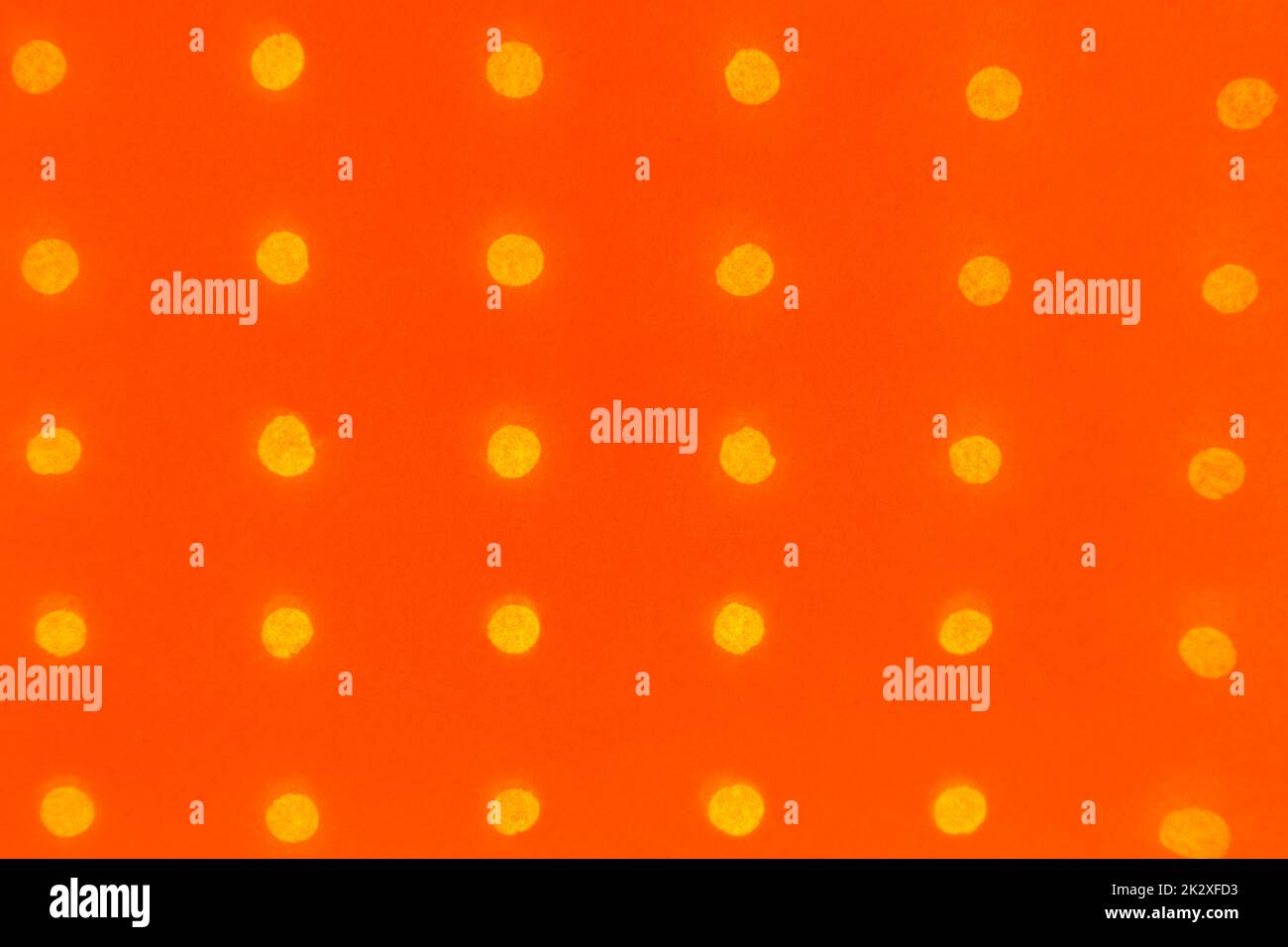 Orange abstract paper background with small round holes arranged in a ...