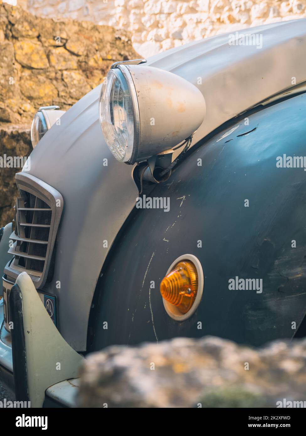A close-up of the front of an old Citroen 2 CV, headlamp and hood in ...