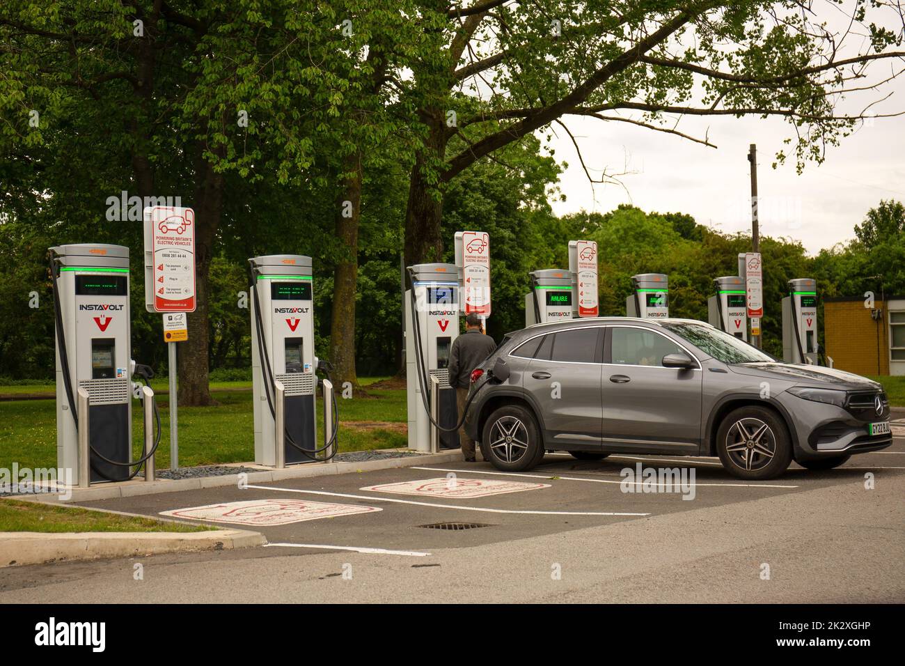 A man charging his grey Electric Mercedes vehicle in the station of ...