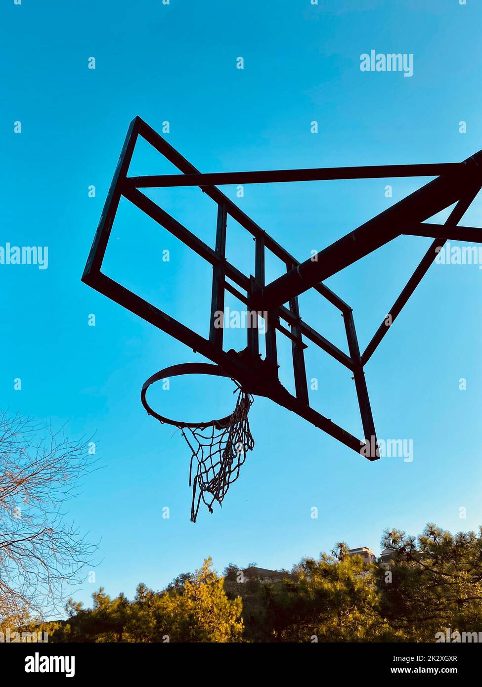 A vertical low angle shot of an old basketball hoop under a blue sky ...