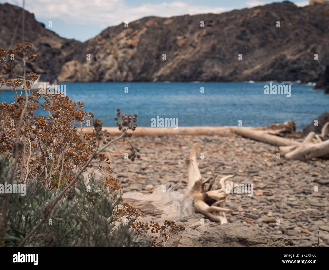 An aerial view of Gran de Culip rocky beach surrounded by emerald water ...