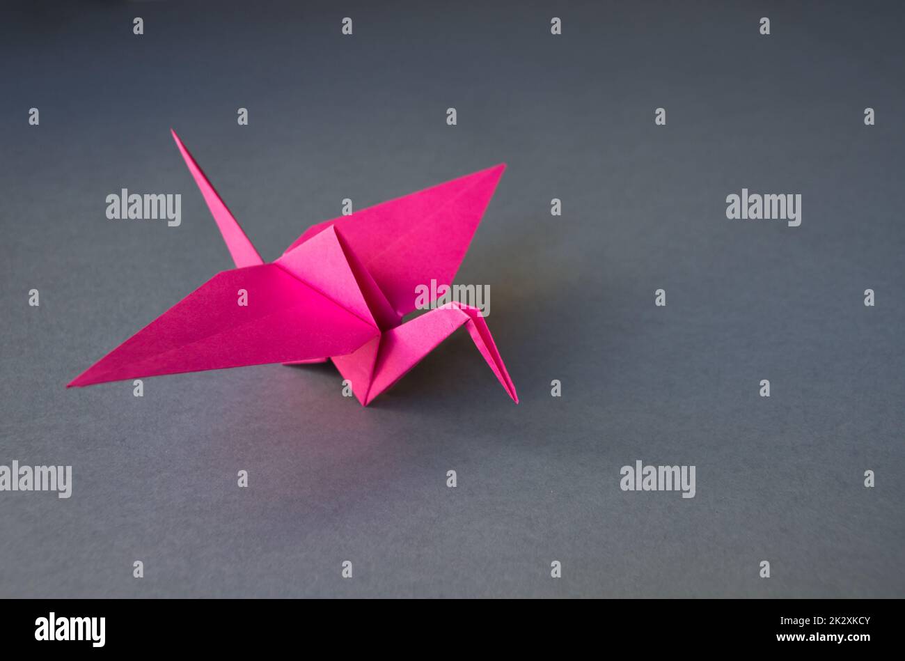 Pink paper crane origami isolated on a grey background Stock Photo - Alamy