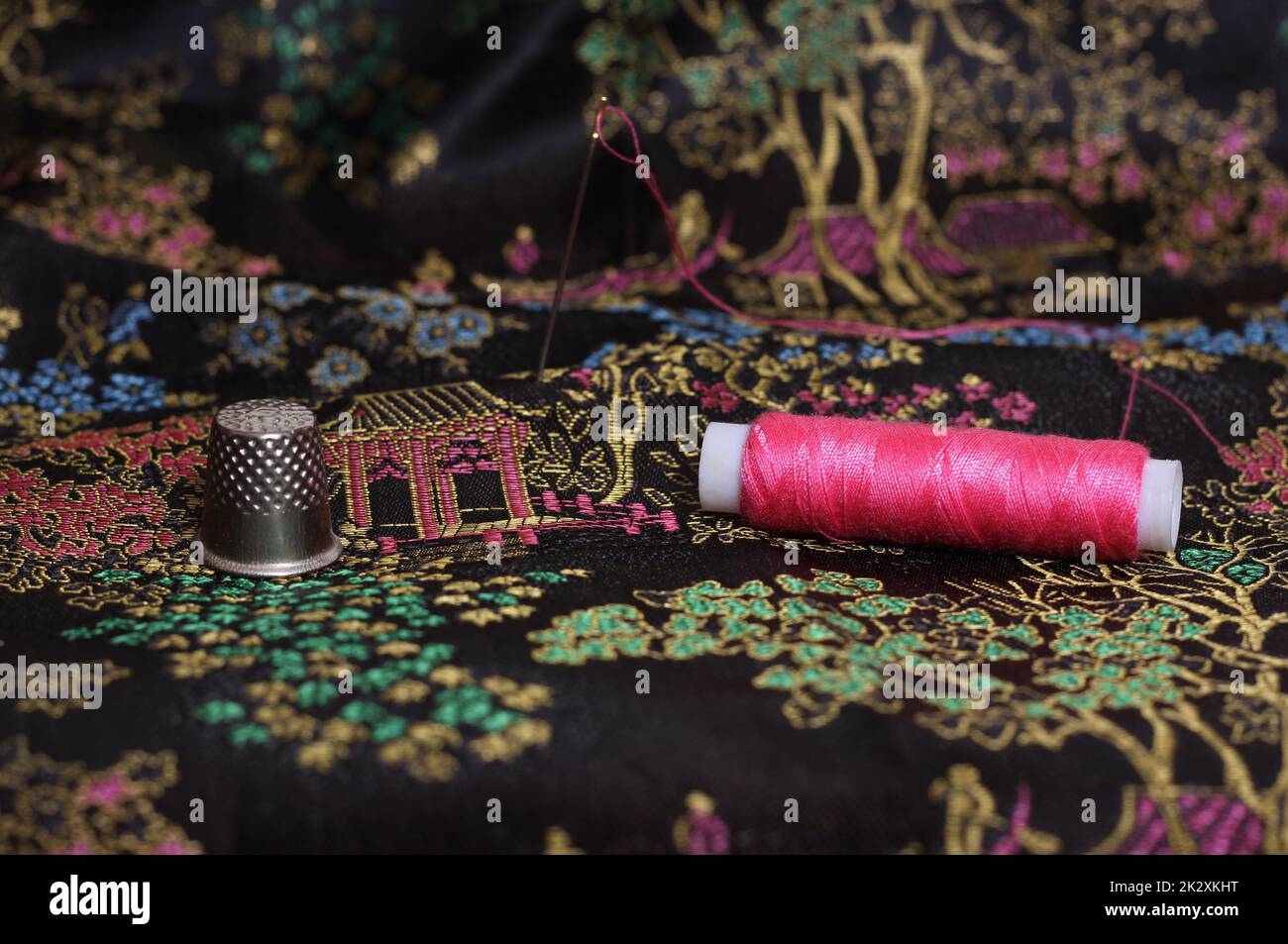 Pink Thread and Thimble on Vintage Chinese Black Silk Stock Photo - Alamy